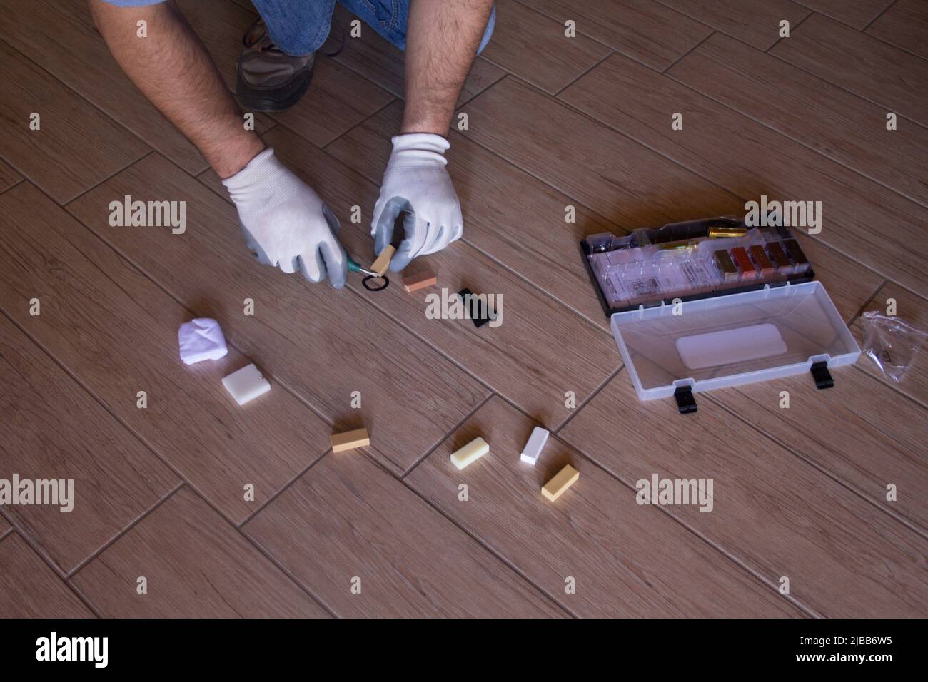 Image of the hands of a handyman repairing a splinter on a tile on the ...