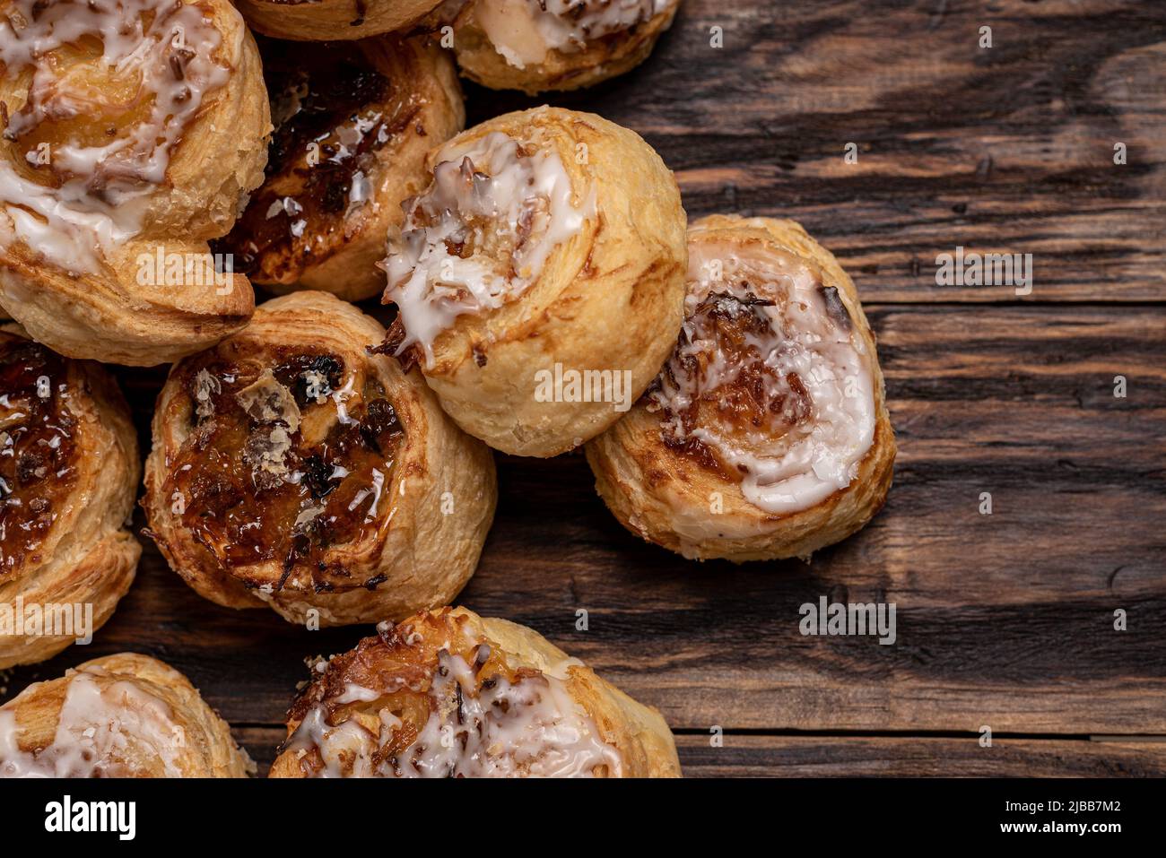 Homemade glazed puff pastry cinnamon rolls with custard and raisins on ...