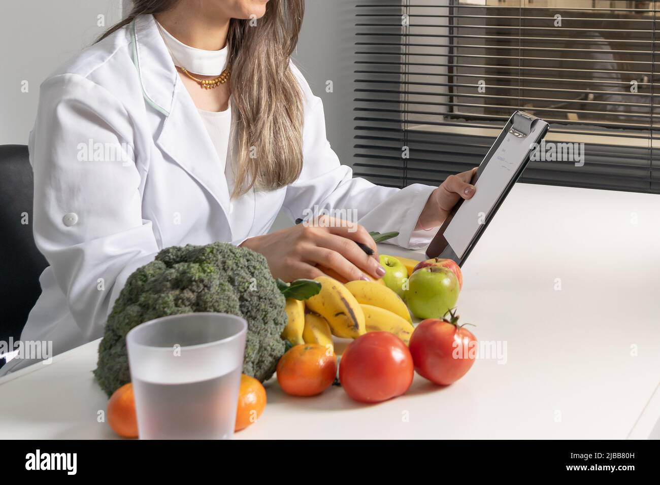 Smiling female nutritionist in her office, writing diet plan showing ...