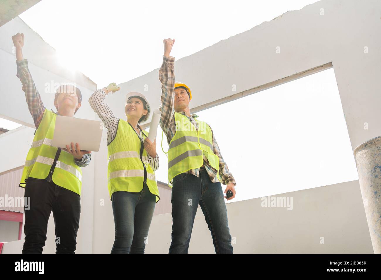 Engineer team and contractor raise their hands up together in factory ...