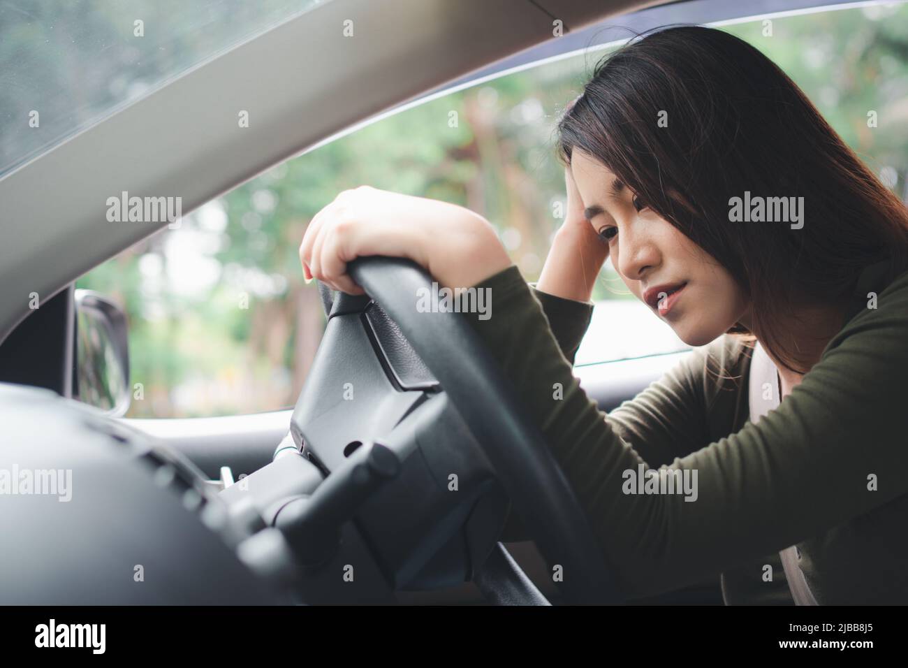 Stressed and unhappy Asian woman driver sitting inside her vehicle and ...