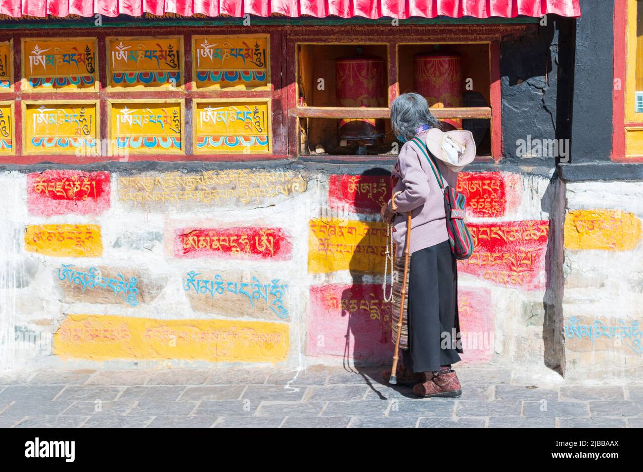Tibetan pilgrim and Prayer wheels along a pilgrim route in Lhasa, Tibet ...