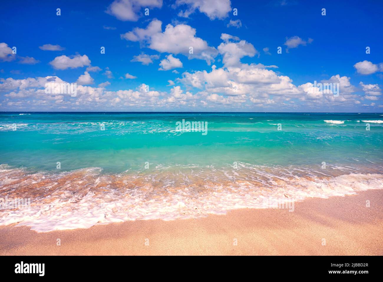 Golden sand beach by the sea with emerald green sea water and blue sky ...