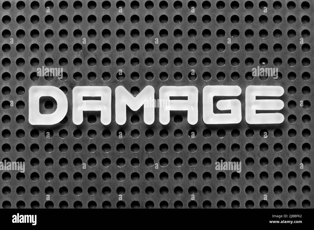 White alphabet letter in word damage on black pegboard background Stock ...