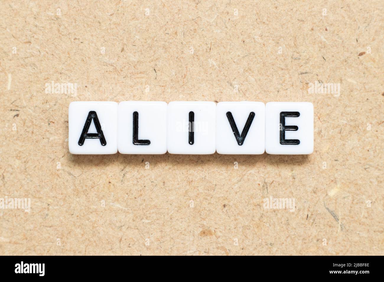 White tile alphabet letter with word alive on wood background Stock ...