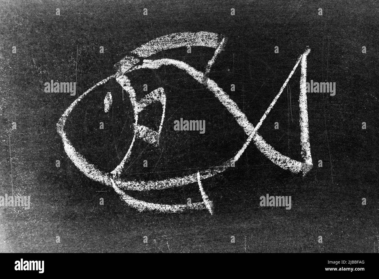 White color chalk hand drawing as fish shape on black board background ...