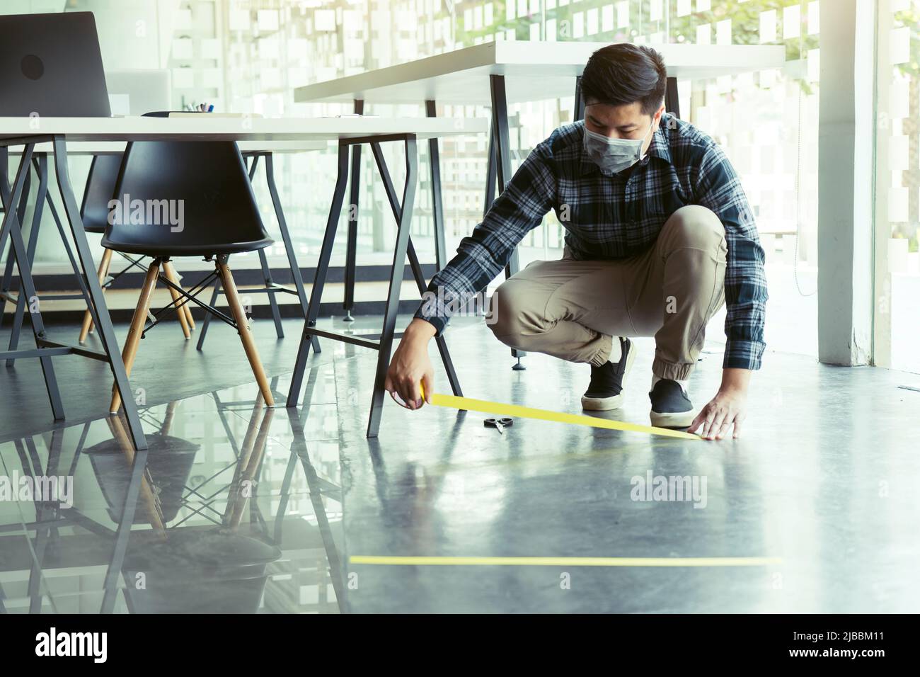 Male workers preparing masking tape to symbolize social distances Stock ...