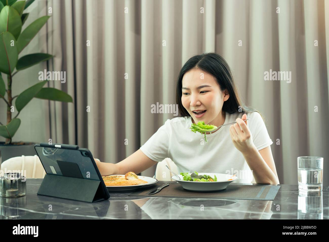 Asian young lady picks up her favorite series on her tablet while ...