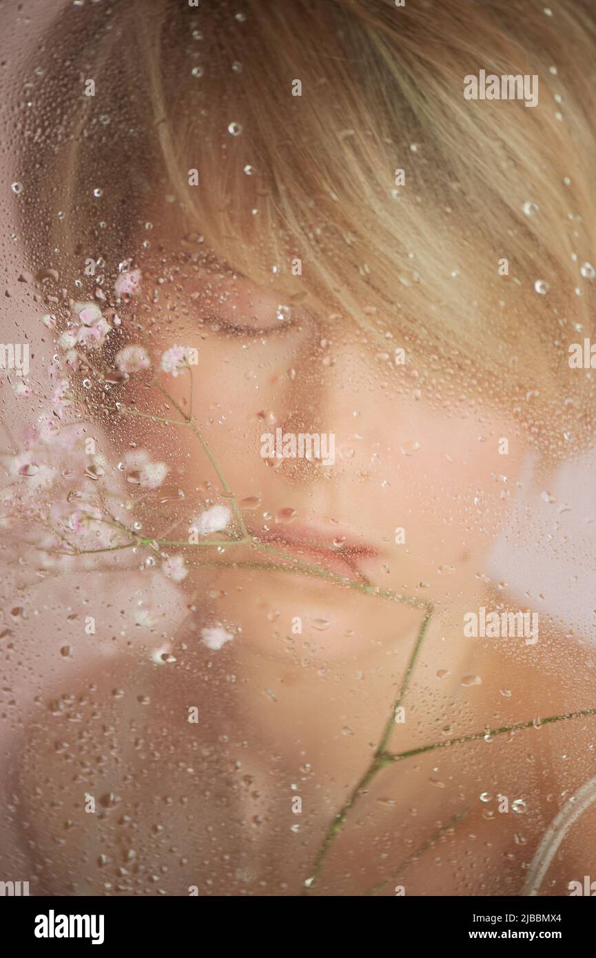 A gentle girl on a pink background, behind fogged glass. Femininity and ...