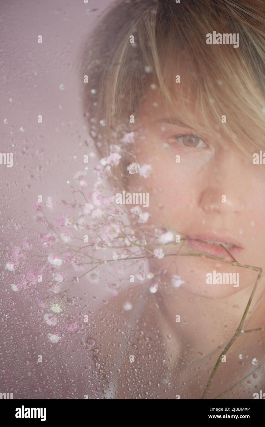 A gentle girl on a pink background, behind fogged glass. Femininity and ...