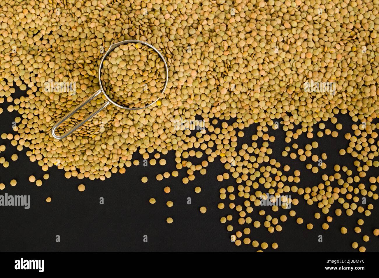 Dry green lentils with stainless steel scale on black surface, harvest ...