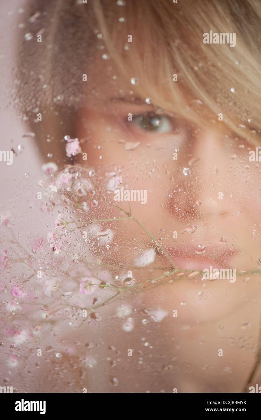 A gentle girl on a pink background, behind fogged glass. Femininity and ...