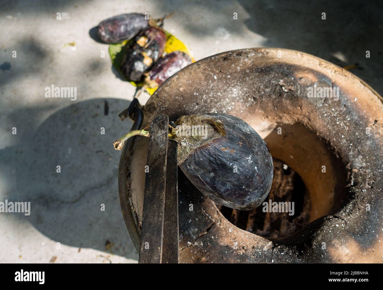 Whole roasted eggplant or brinjal in a traditional clay Angeethi or ...