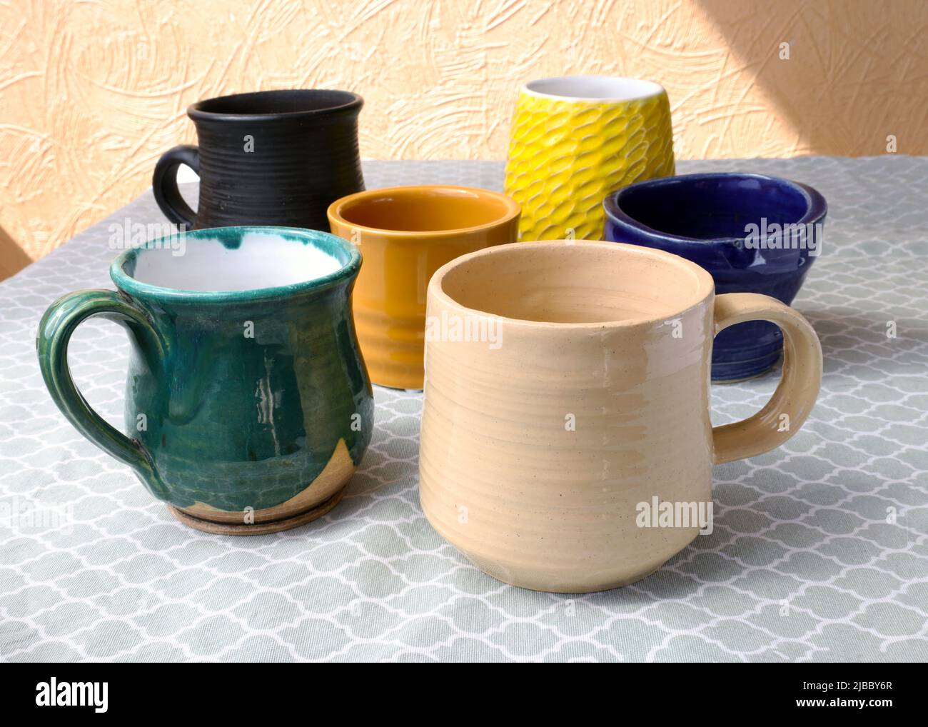 Ceramic cups of different colors and sizes close-up. Multi-colored cups ...