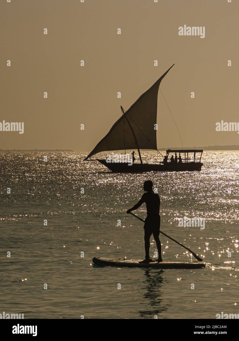 Silhouette of a person on a sup board and a traditional sailing dhow ...