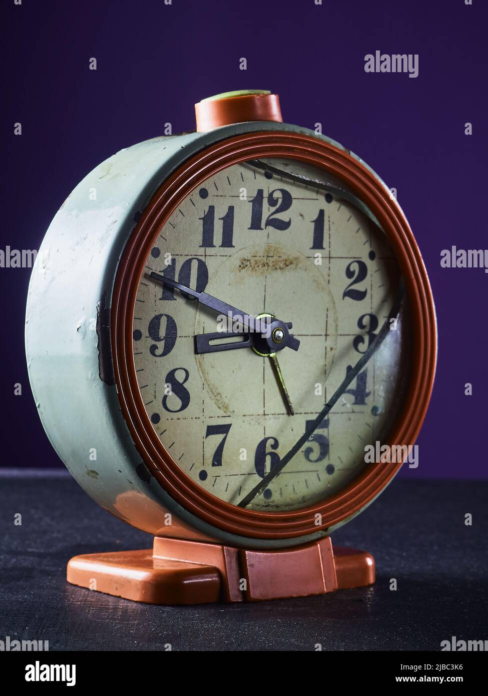 Dirty old broken rusty alarm clock. Broken dial. Red body violet ...