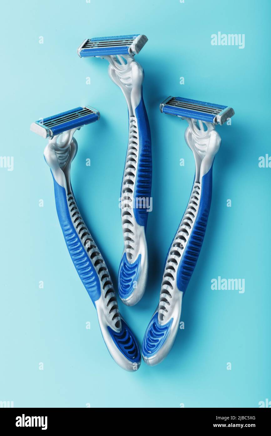 Three shaving machines on a blue background with free space, top view ...