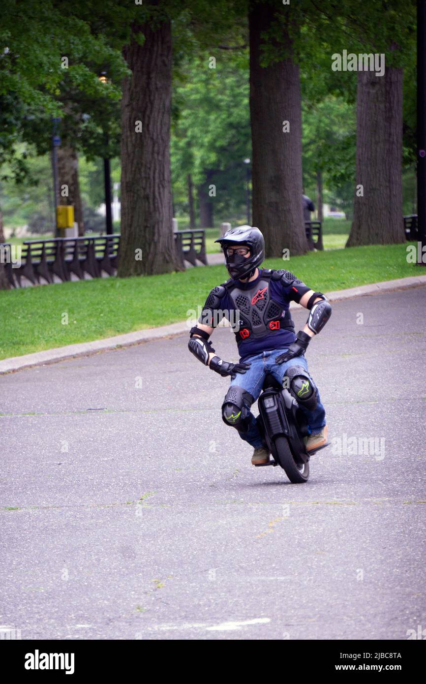 A young man wearing lots of protective gear rides an electric Unicycle ...