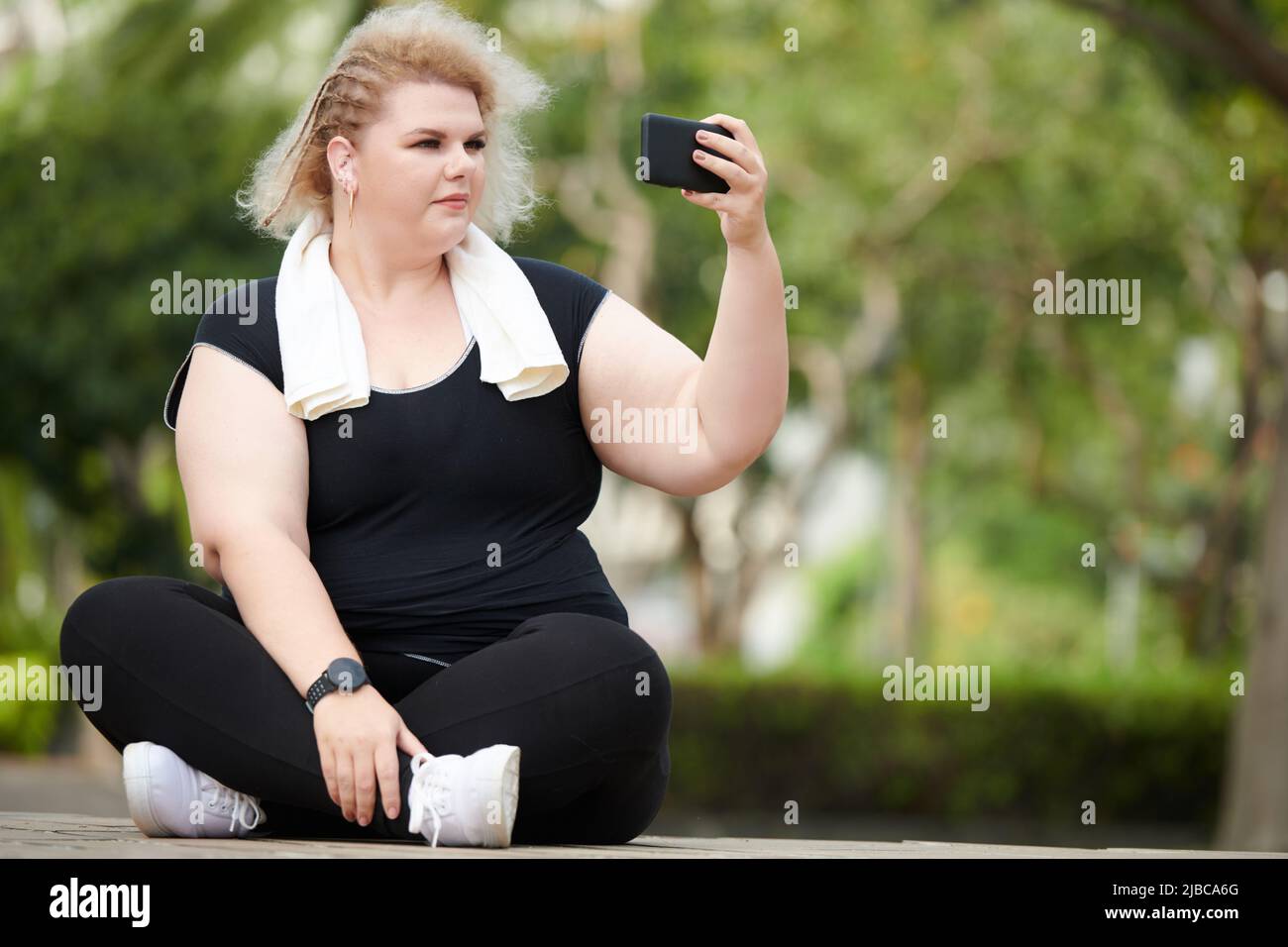 Plus size woman filming video for her blog after working out outdoors ...
