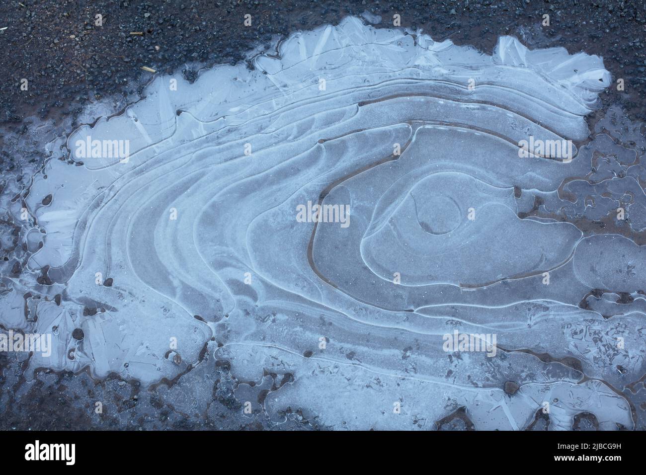 Frozen puddle with circular ice patterns Stock Photo - Alamy