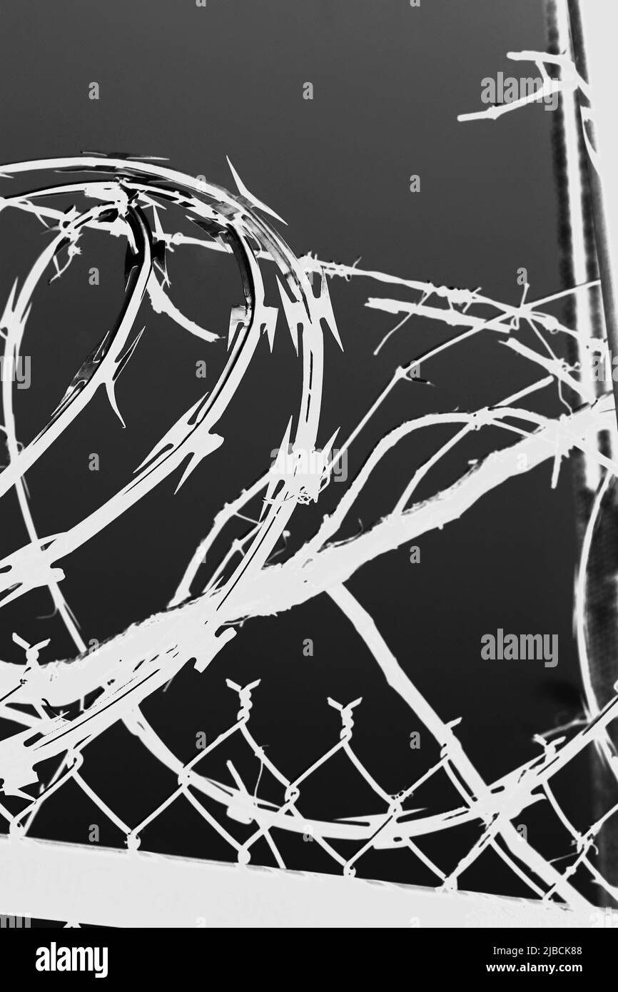 Razor wire fence protecting something important in black and white film ...