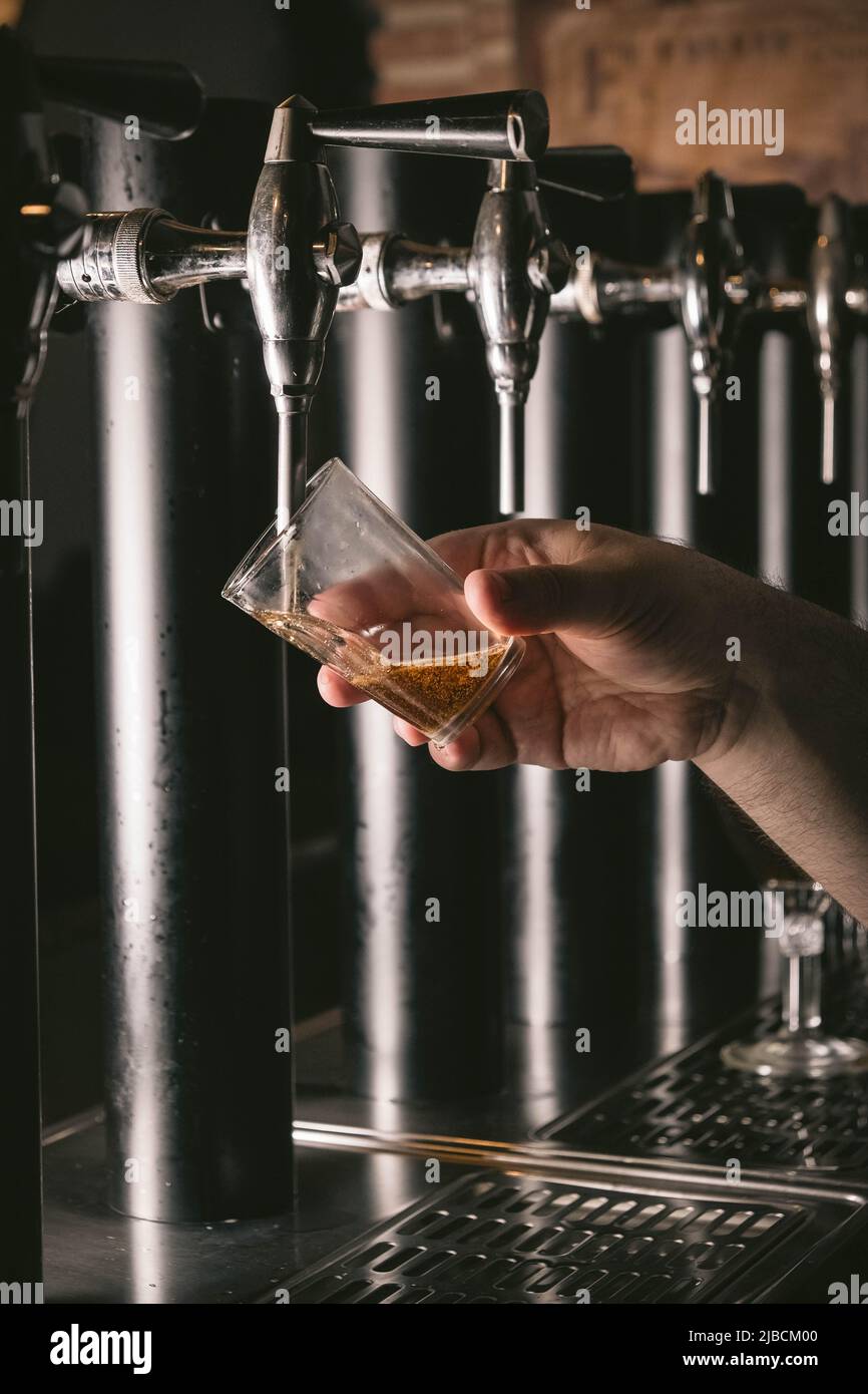 bartender hand at beer tap pouring a draught beer in glass serving in a restaurant or pub Stock ...