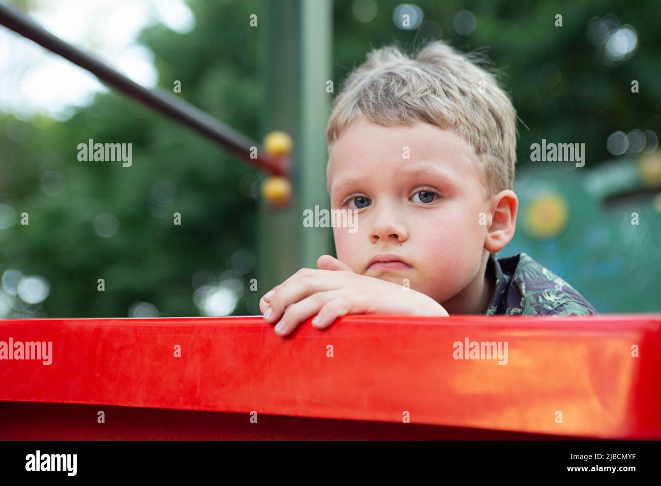 Sad boy sitting on the slide on playground.Closeup portrait Stock Photo ...
