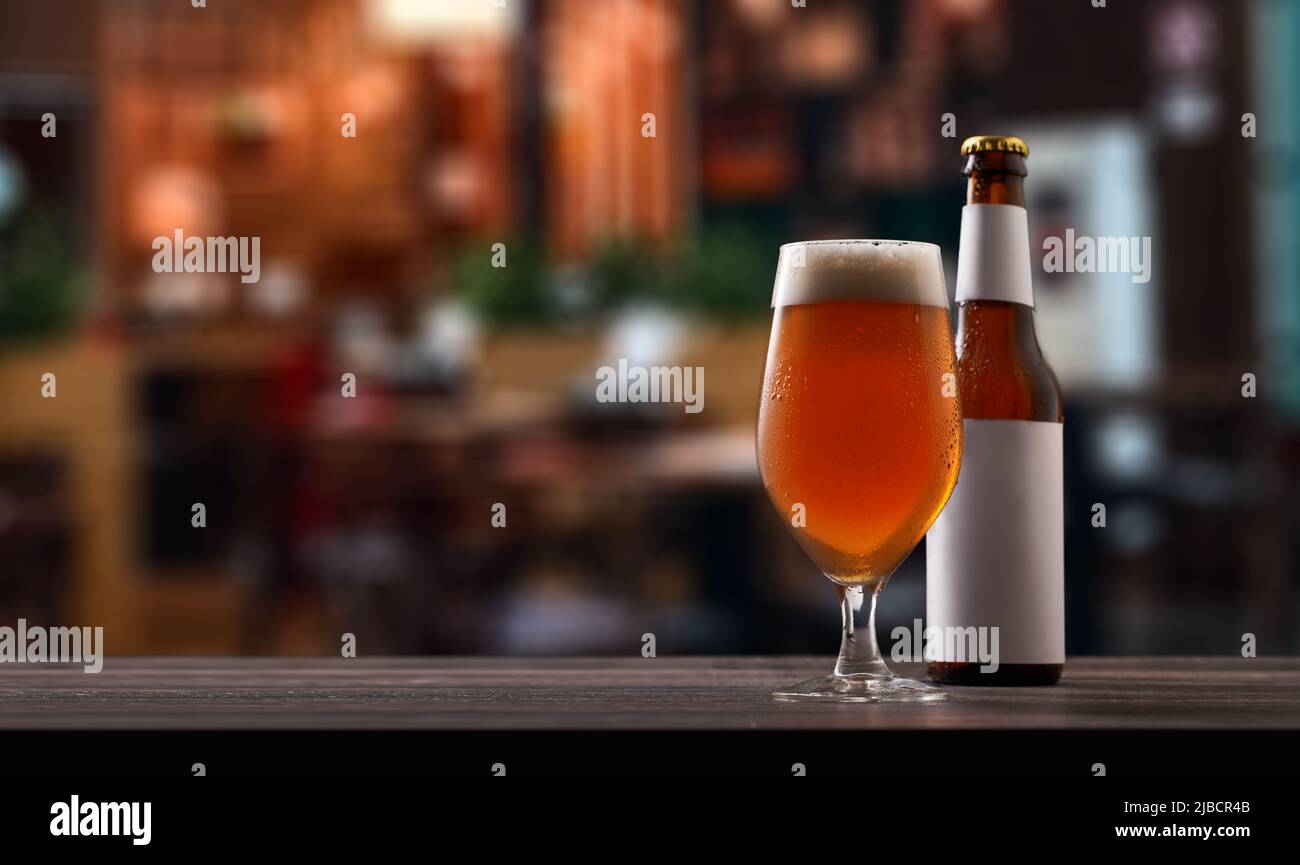Bottle and glass of beer on counter in pub. Alcoholic beverage over pub ...