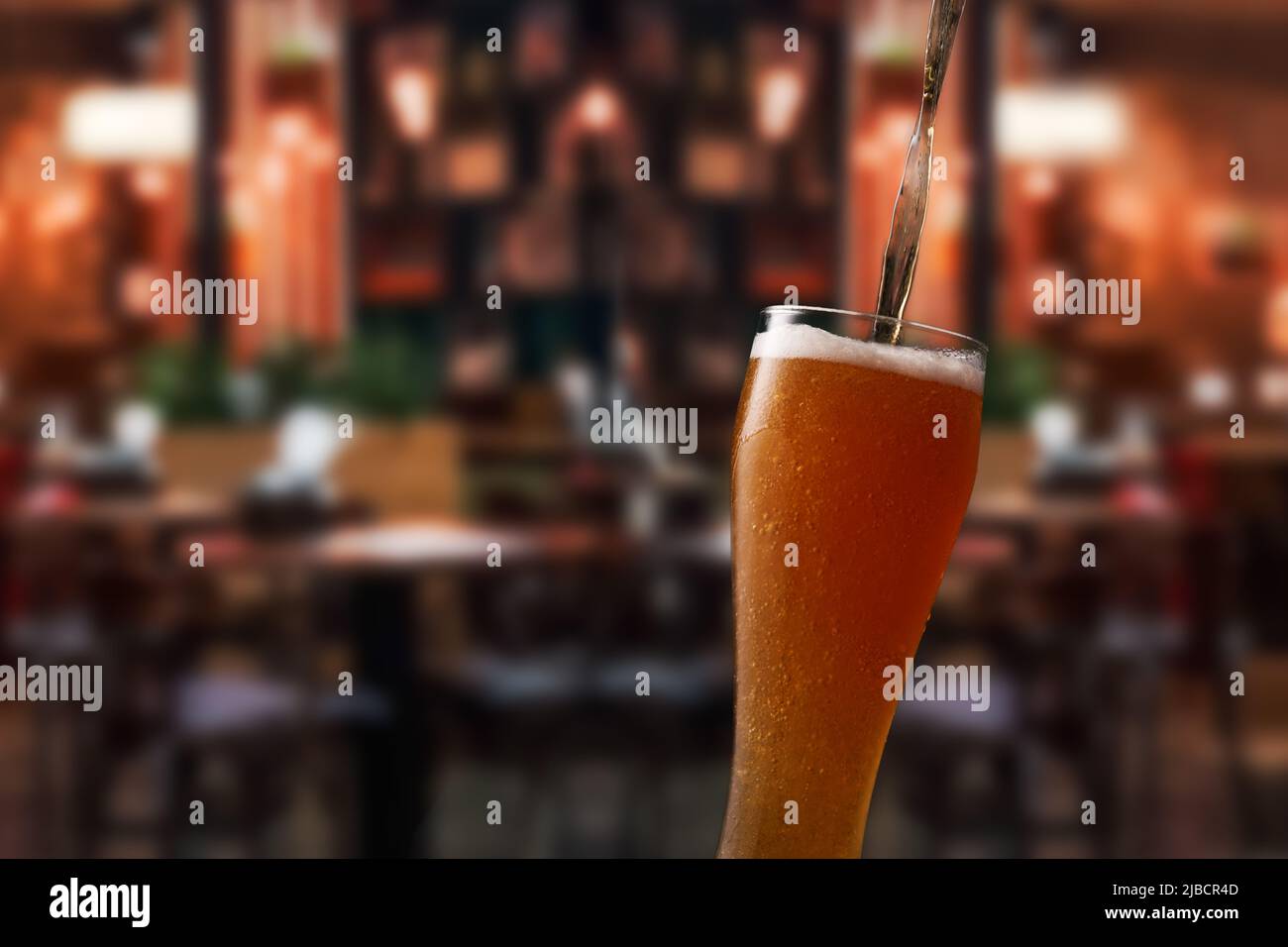 Pouring beer into glass at the bar counter. Alcoholic beverage over pub ...