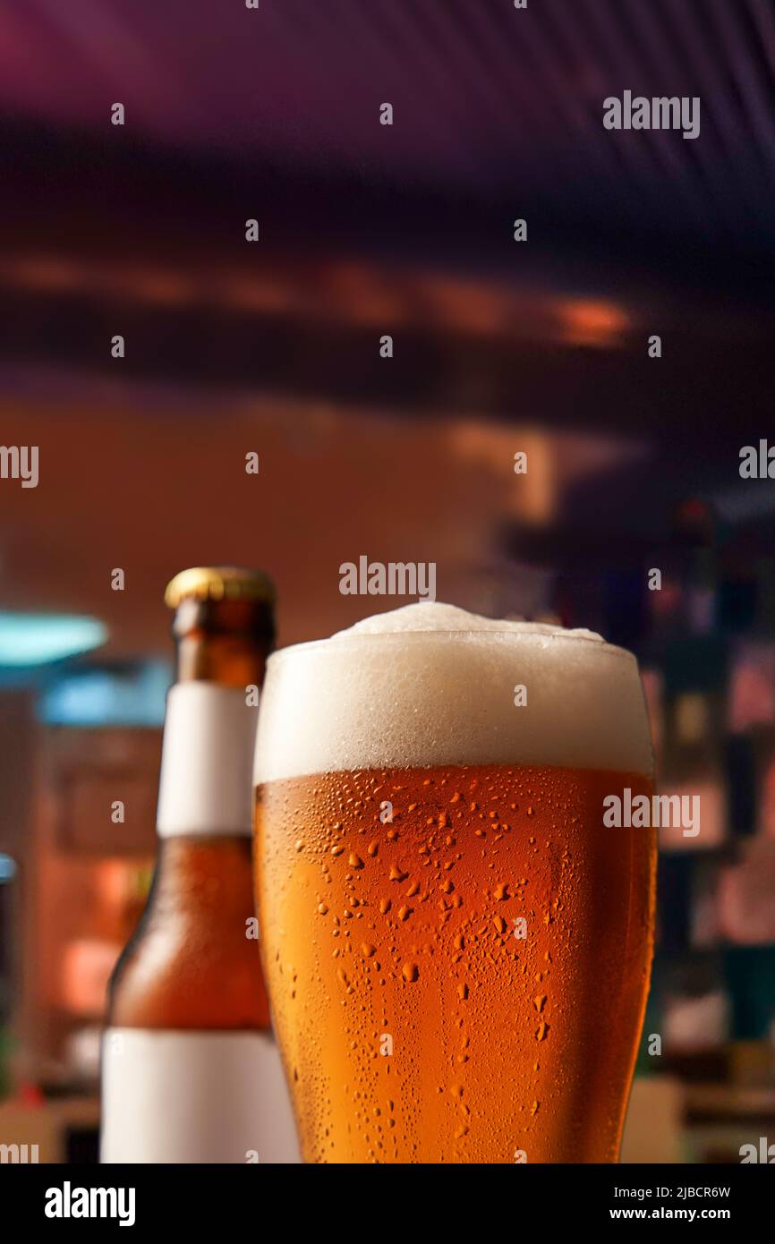 Bottle and glass of beer on counter in pub. Alcoholic beverage over pub ...