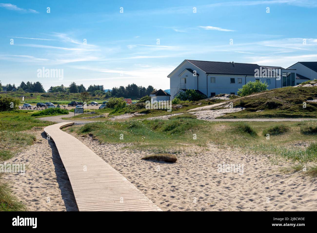 A wooden boardwalk from the beach to Sola Strand Hotel resort and car ...