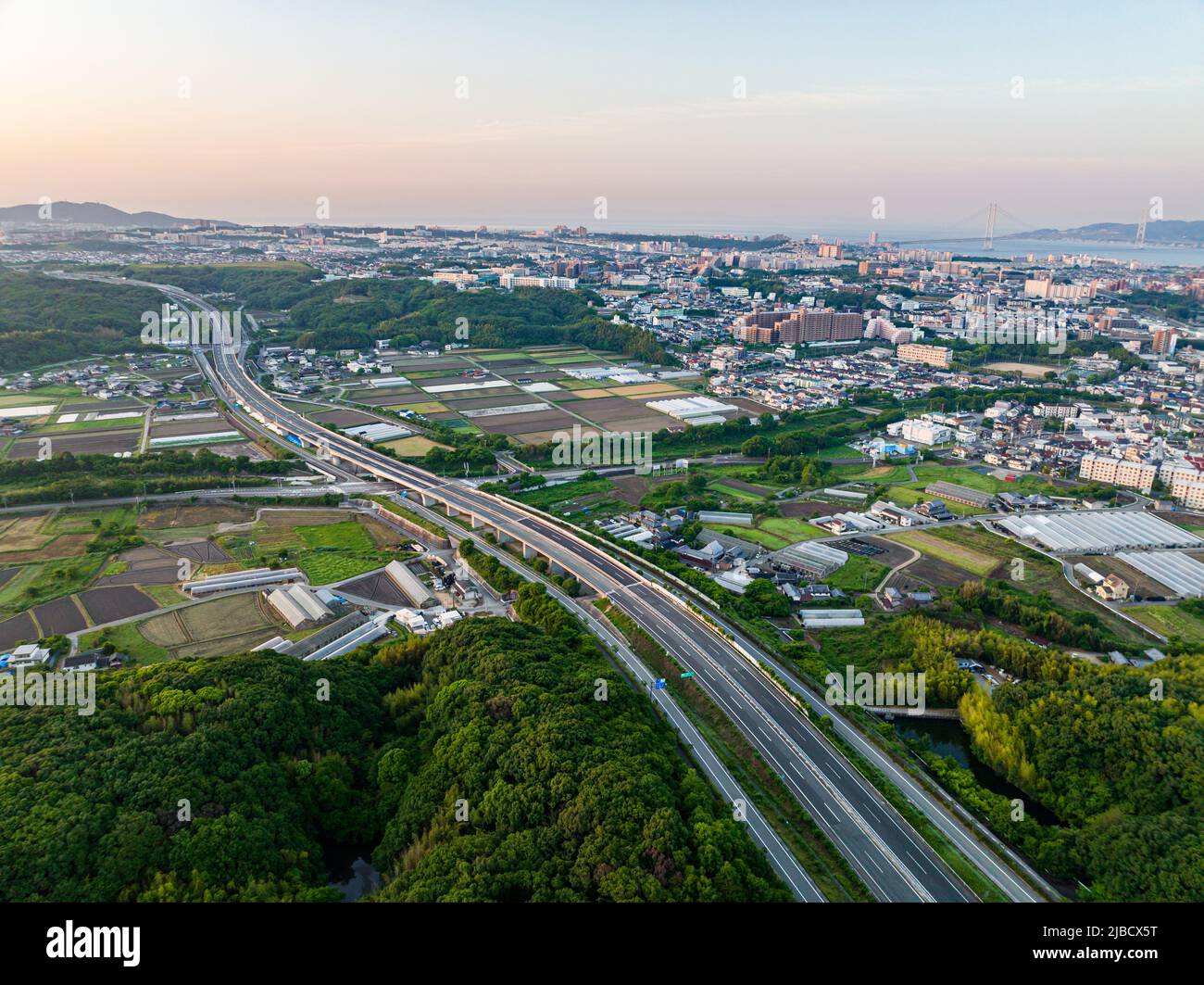 View of highway through rice fields and green hills with sprawling town ...