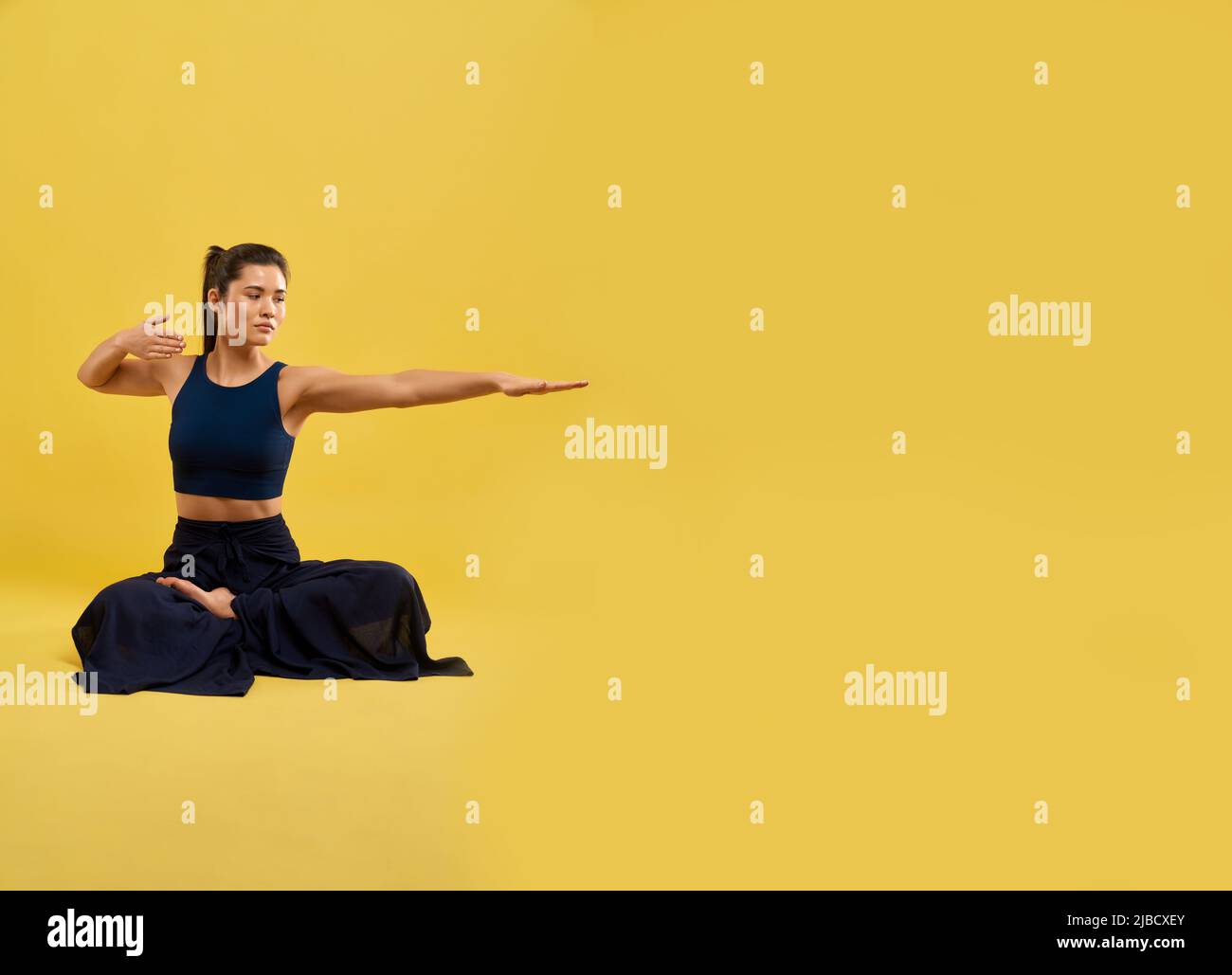 Serious woman sitting in meditation pose, holding arms bent and ...