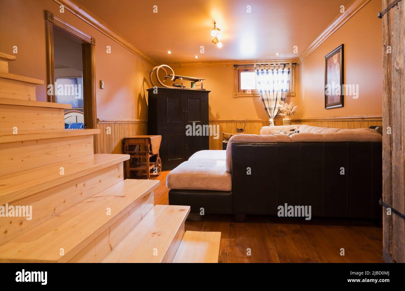 Clear varnished pine wood stairs and beige sectional sofa in basement ...