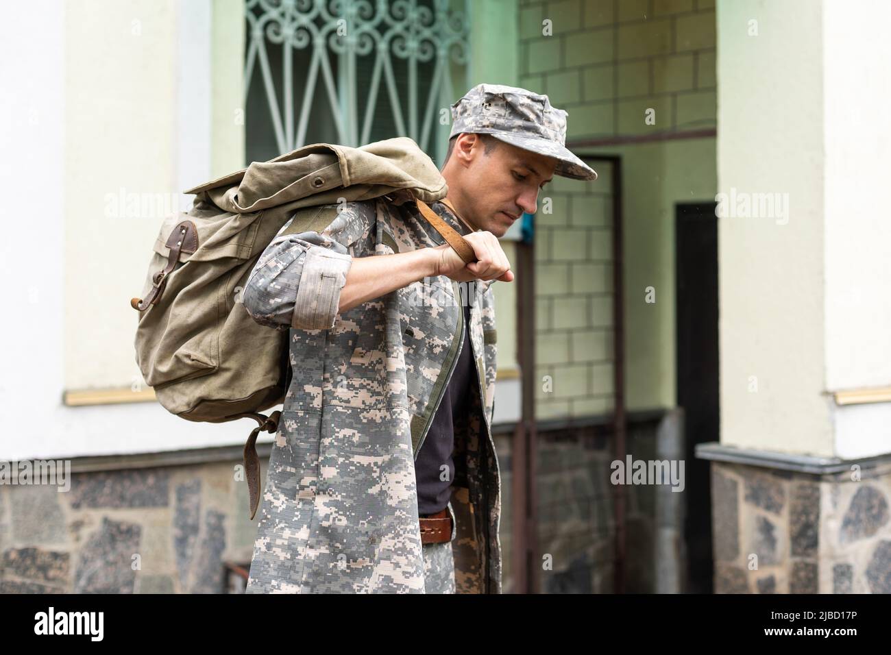 Photo of soldier in camouflaged uniform holding olive colored backpack ...