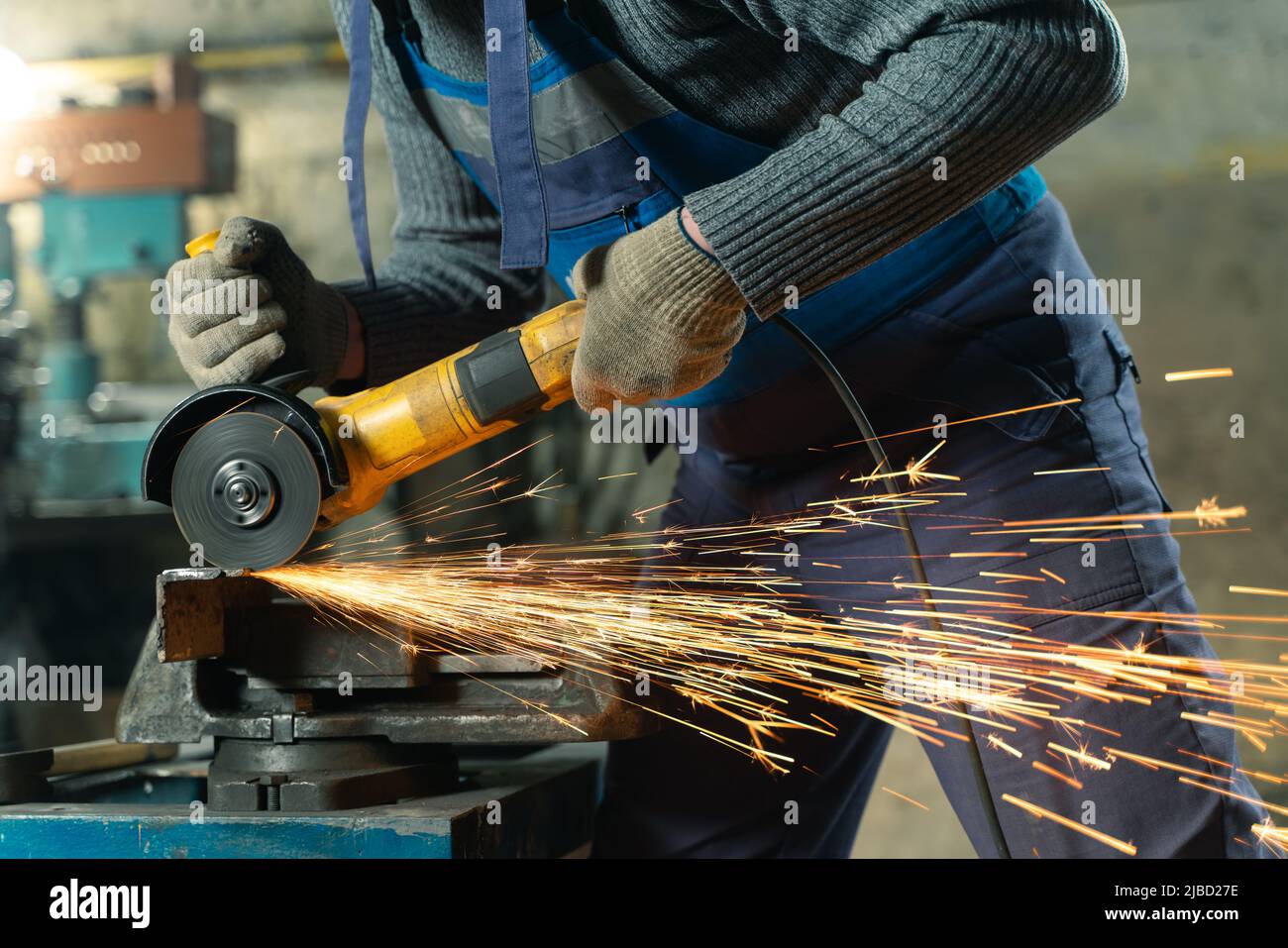 Locksmith in special clothes and goggles works in production. Metal ...