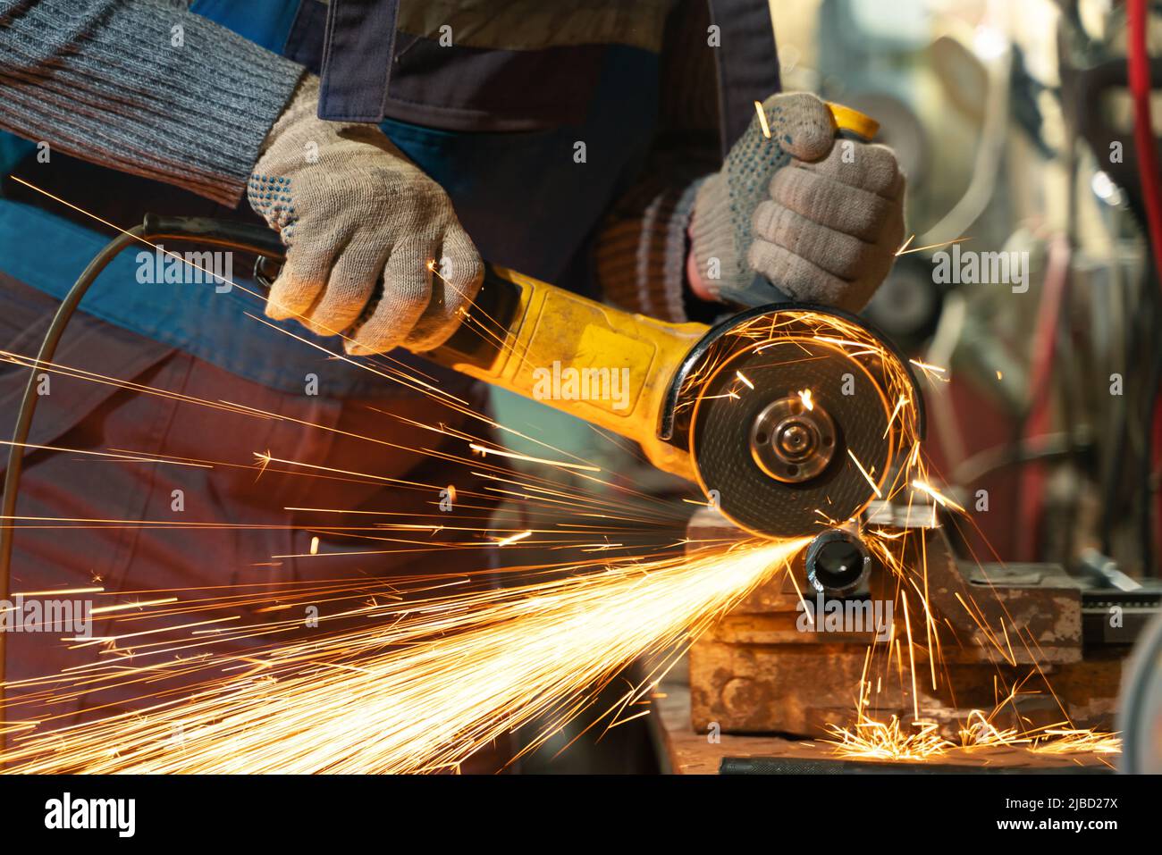 Locksmith in special clothes and goggles works in production. Metal ...