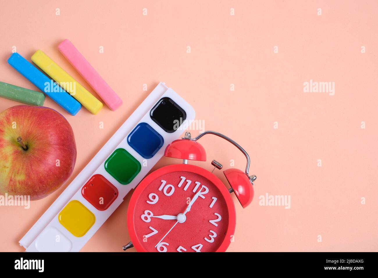 Alarm clock, school supplies and stationery pink background.Preparing ...