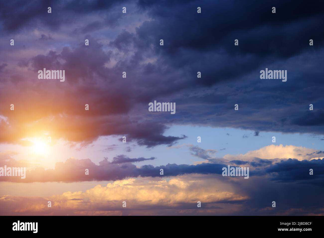 Thunderclouds with breaking rays sun at sunset Stock Photo - Alamy