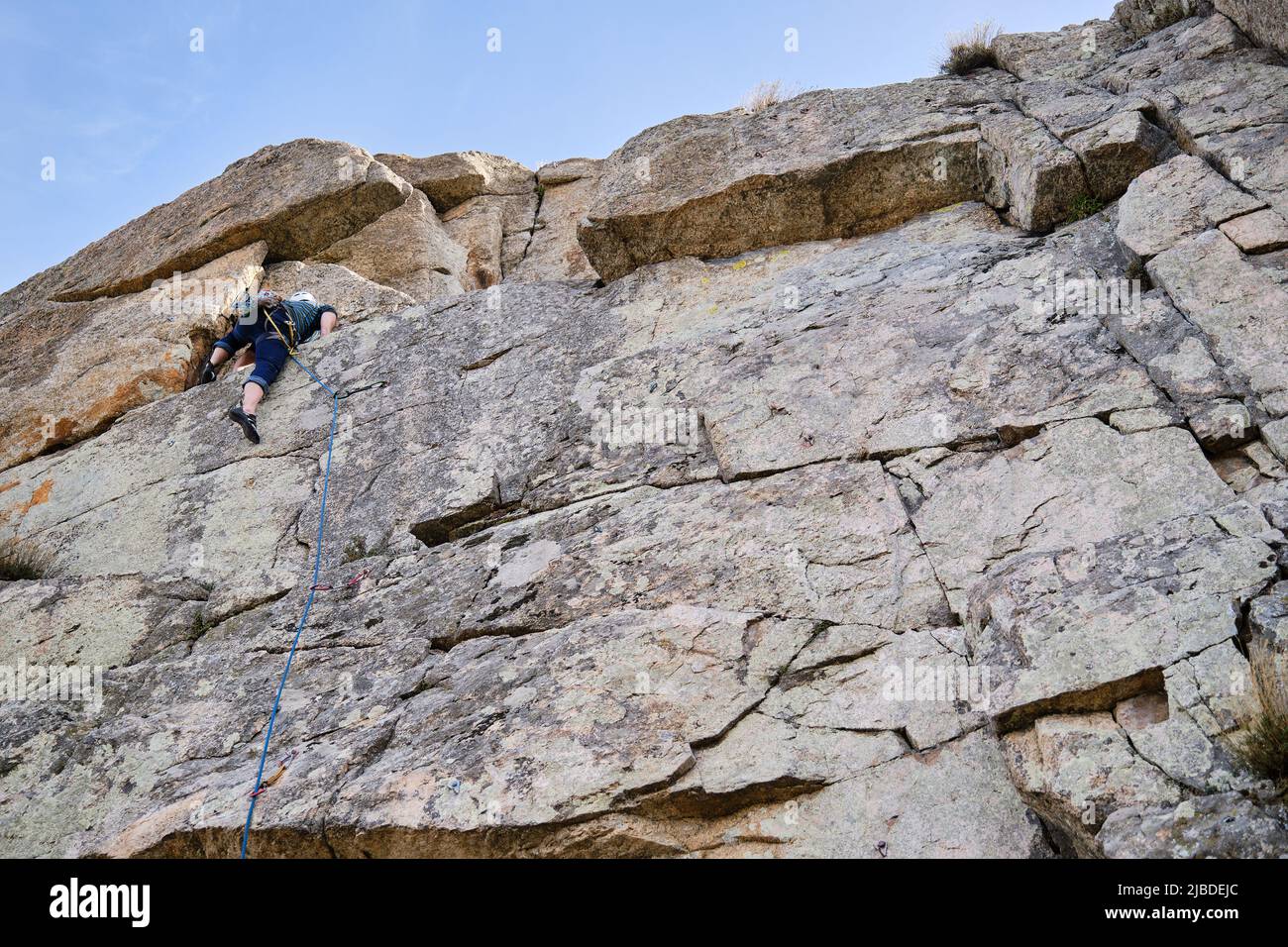 Man climbing up a vertical rock wall Stock Photo - Alamy