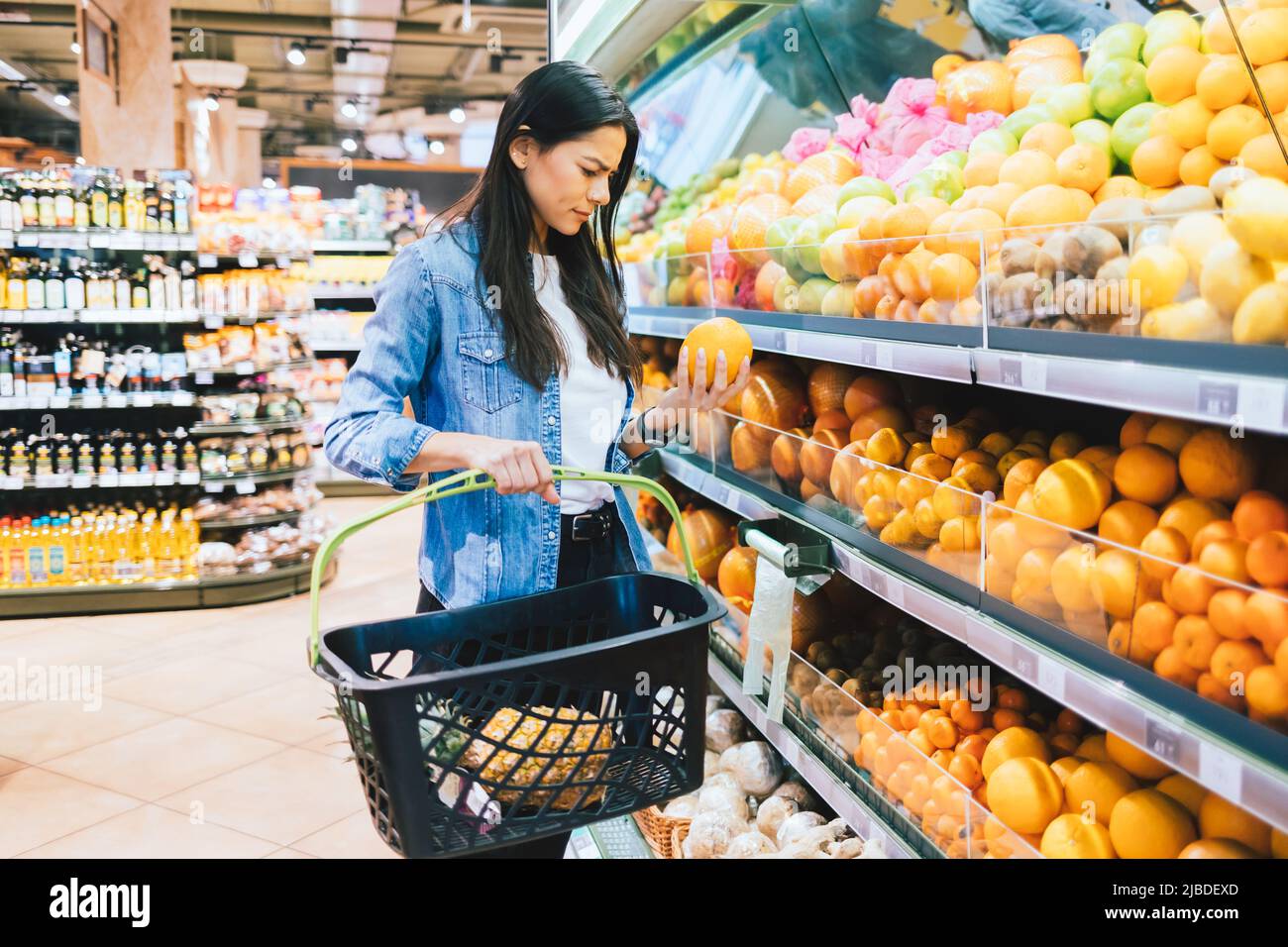 Picky shopper young woman chooses oranges fruits in supermarket Stock ...
