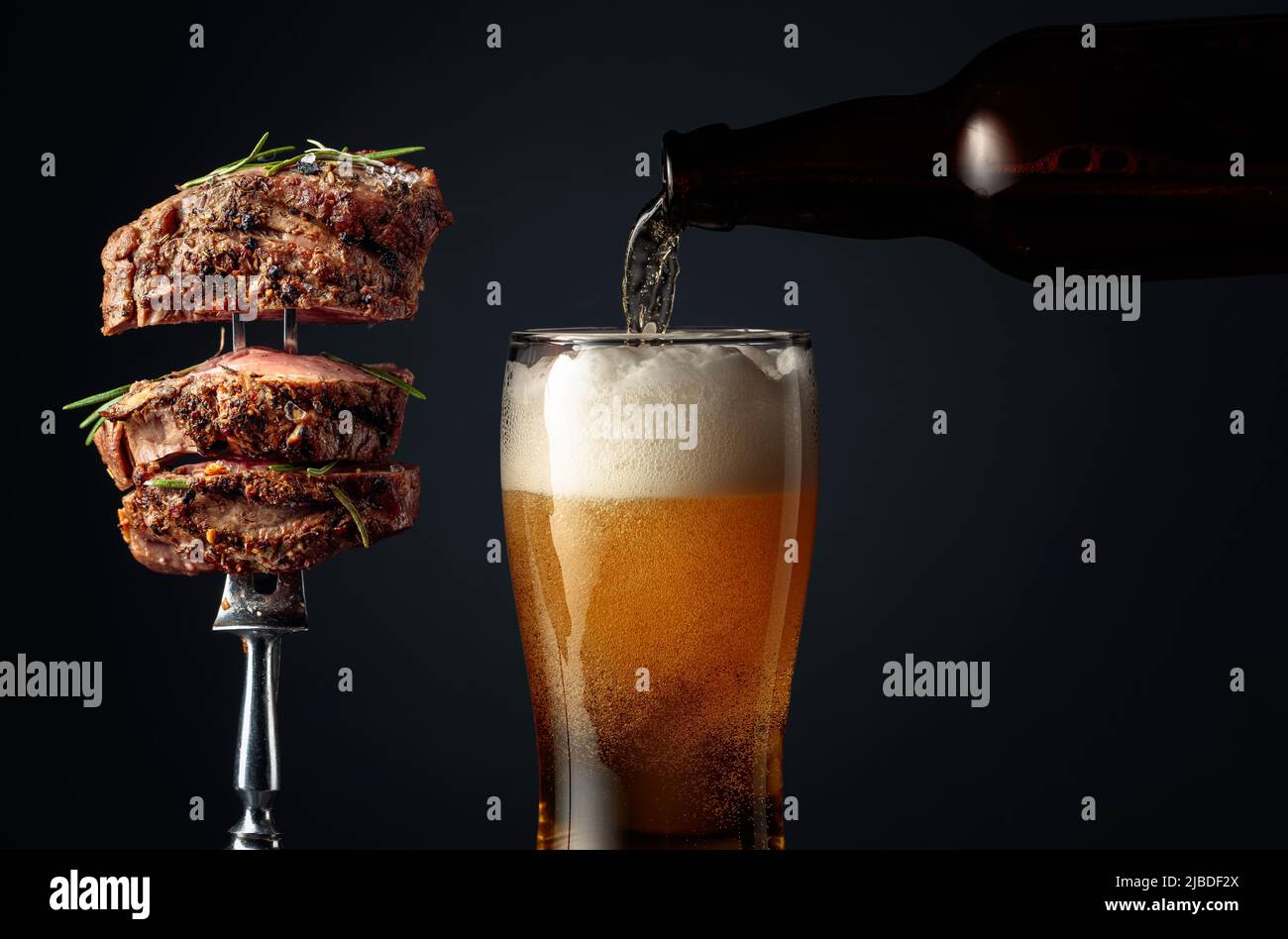 Beer and grilled beef steak with rosemary on a black background. Copy ...