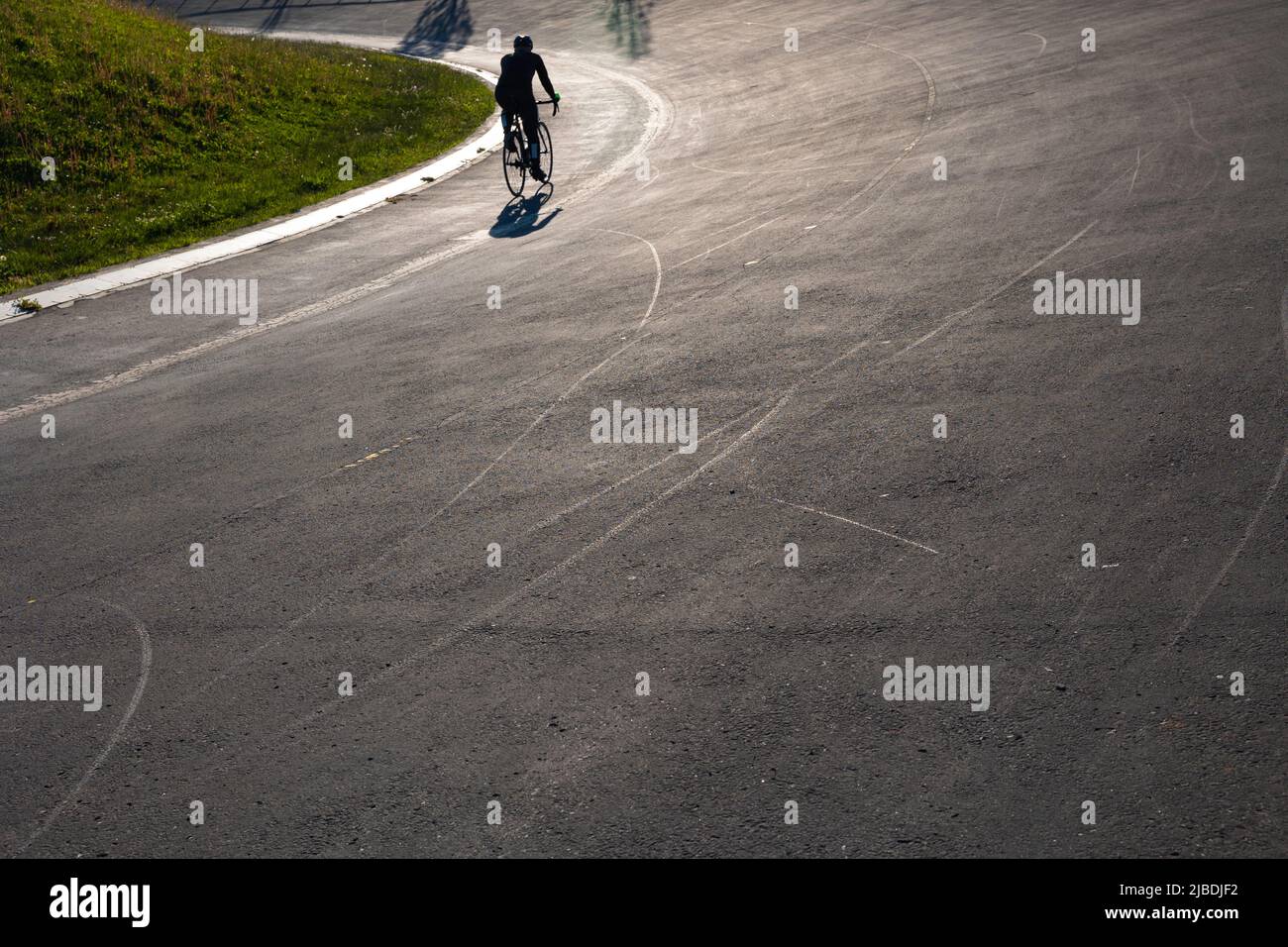 Open air cycle-racing track with a cyclist at sunset in the park ...