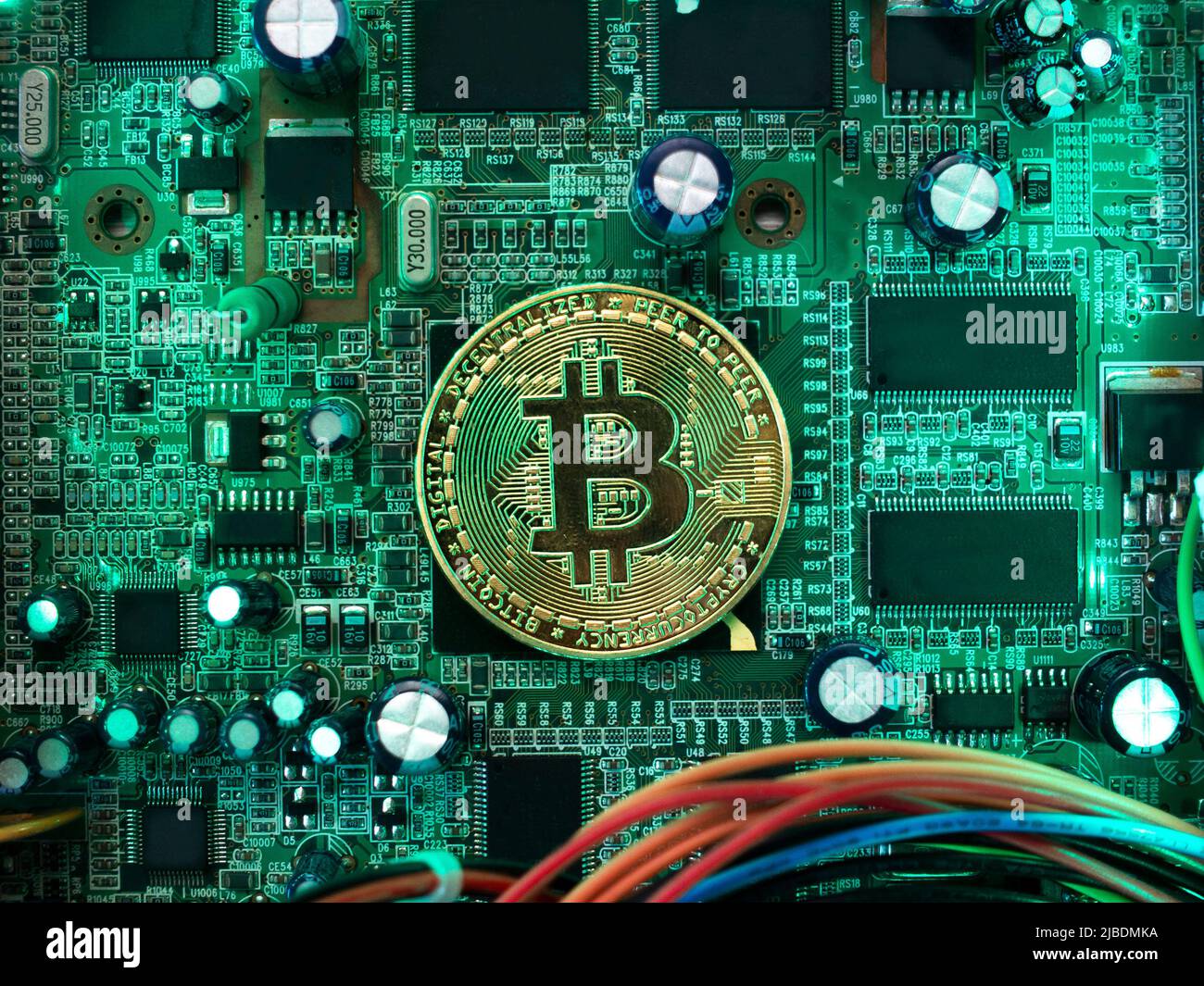 A large yellow bitcoin lies on the microprocessor of a computer board ...