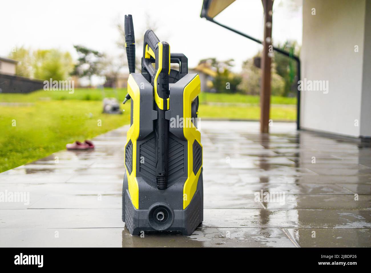 Pressure washer cleaning machine on wet concrete floor near the house ...