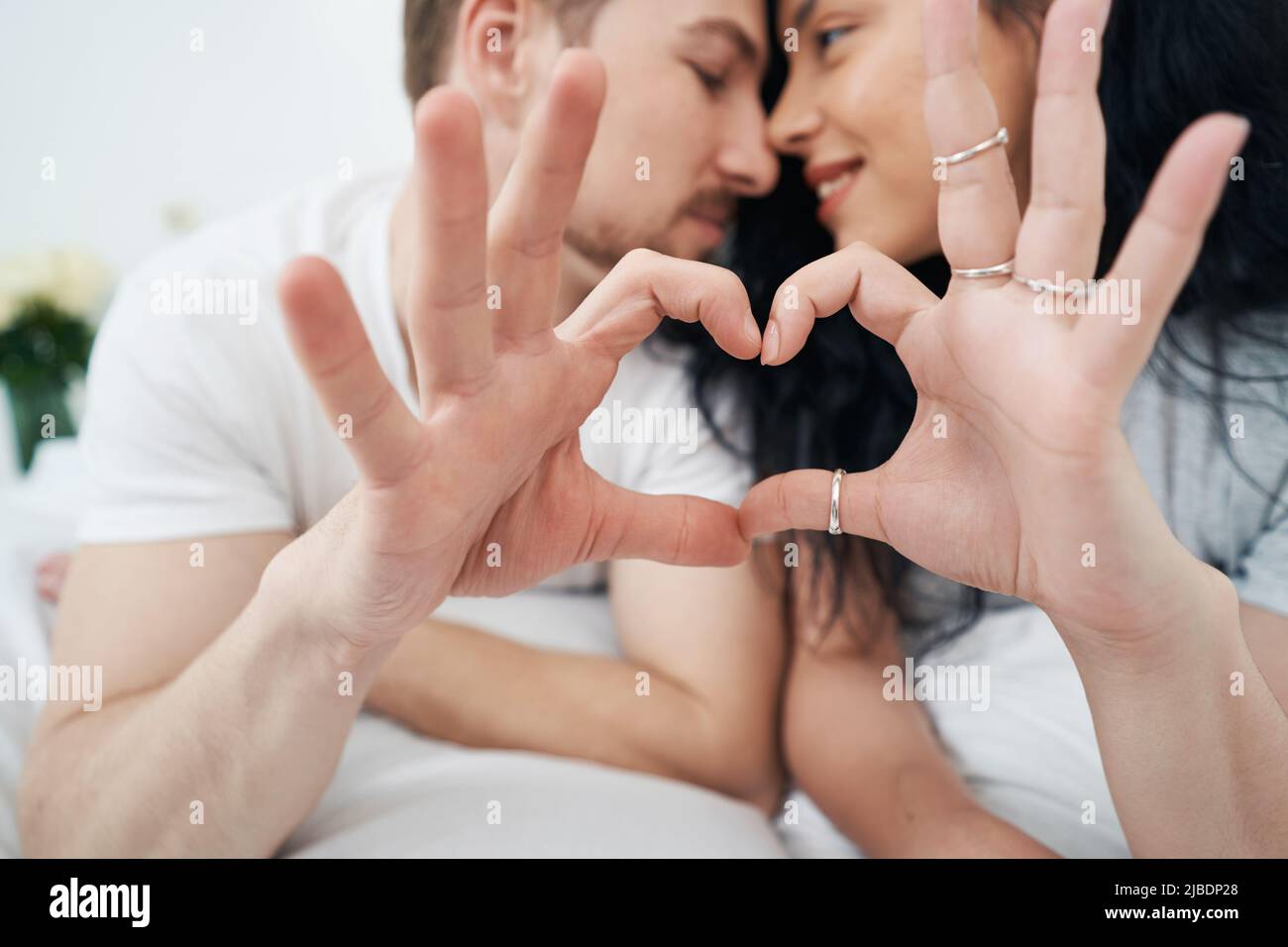 Romantic couple demonstrating heart-hand symbol in bed Stock Photo - Alamy