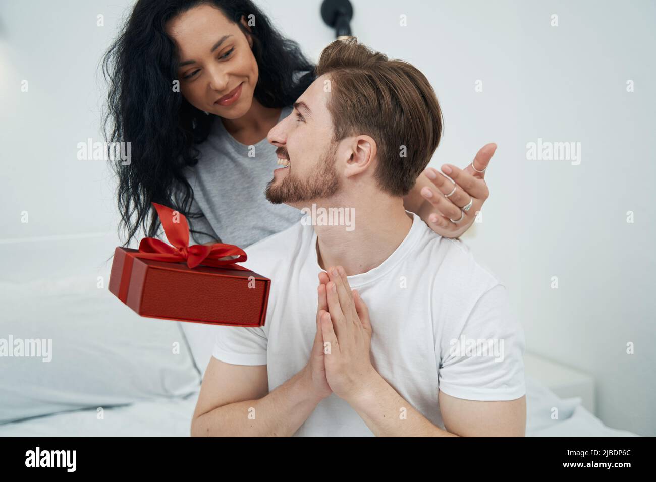 Joyous young man receiving gift from woman Stock Photo - Alamy