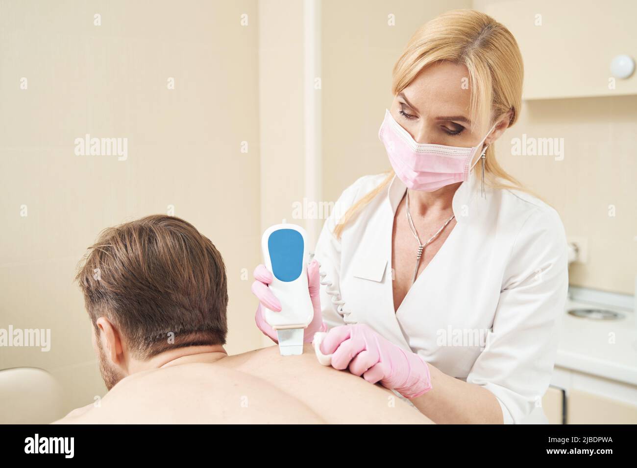 Woman beautician performing ultrasonic purification of skin on male ...