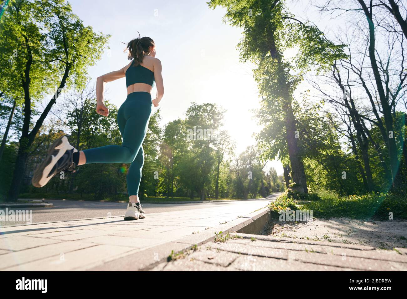 Slim young woman running during free time in park Stock Photo - Alamy