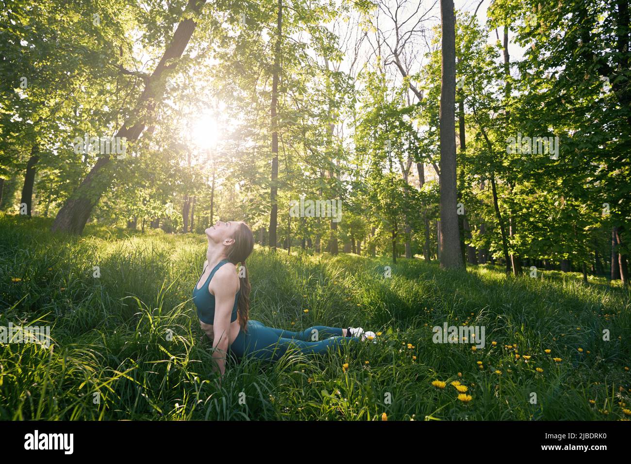 Joyful young woman relaxing in asana in wood Stock Photo - Alamy